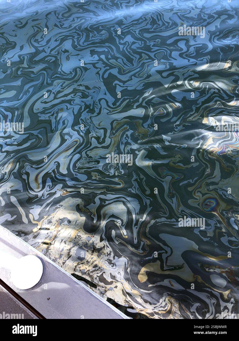 Swirling patterns of oil on the surface of ocean water. This oil slick ...
