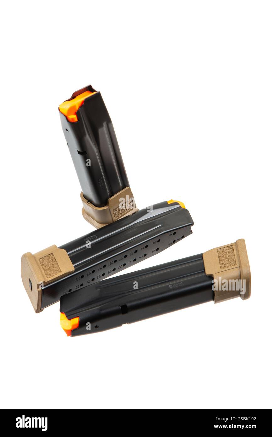 Three black pistol magazines with tan base plates and orange followers ...
