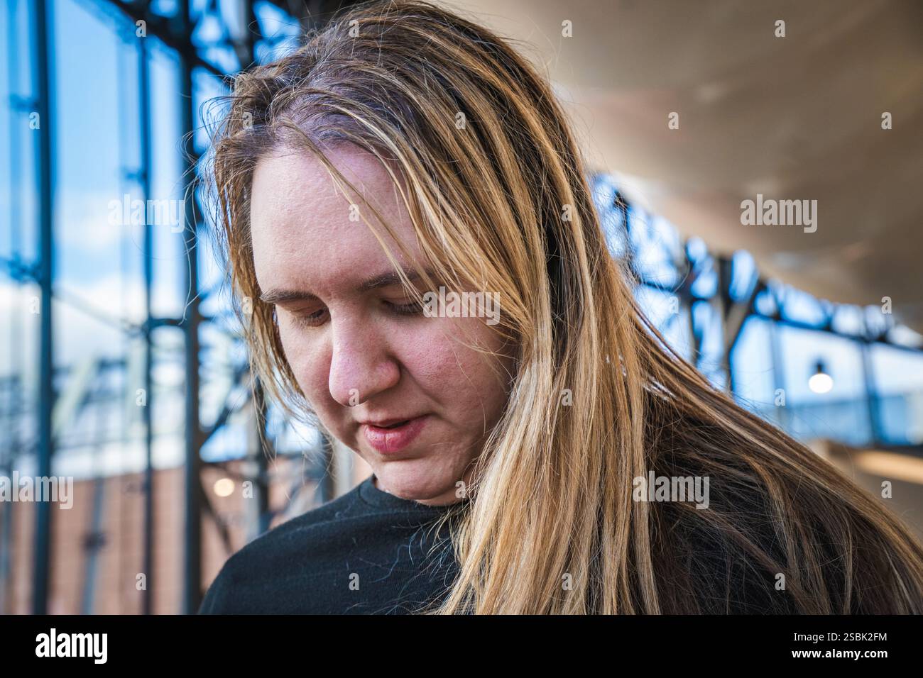 A young woman with long hair stands pensively, absorbed in thought amid ...