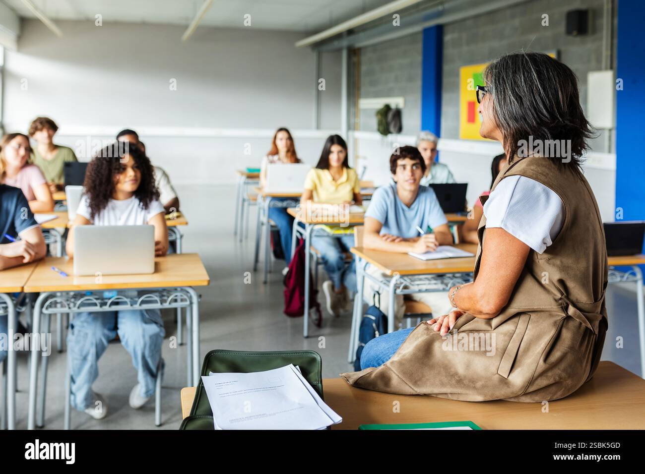 Senior adult teacher giving a lecture to her high school students at ...