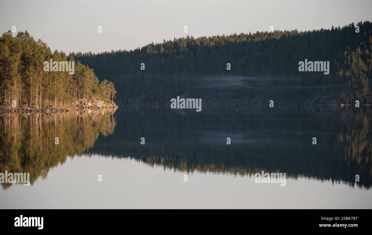Lake scenery with green forests reflected on the calm surface of water ...
