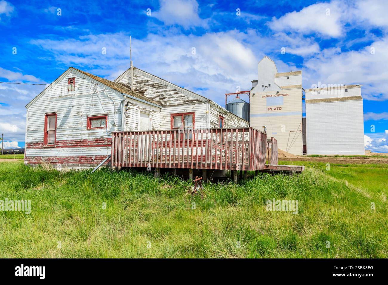 House with a porch and a barn in the background. The barn is white and ...