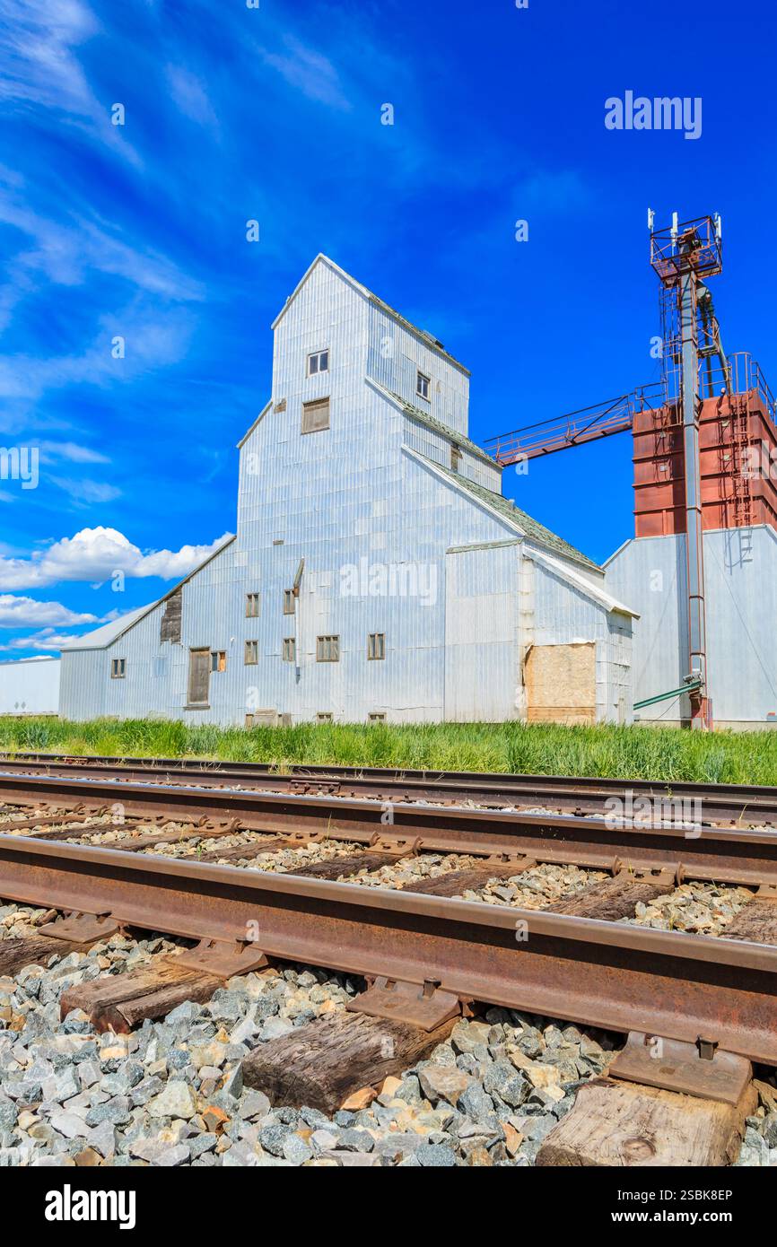 Train tracks with a grain silo in the background. The silo is old and ...
