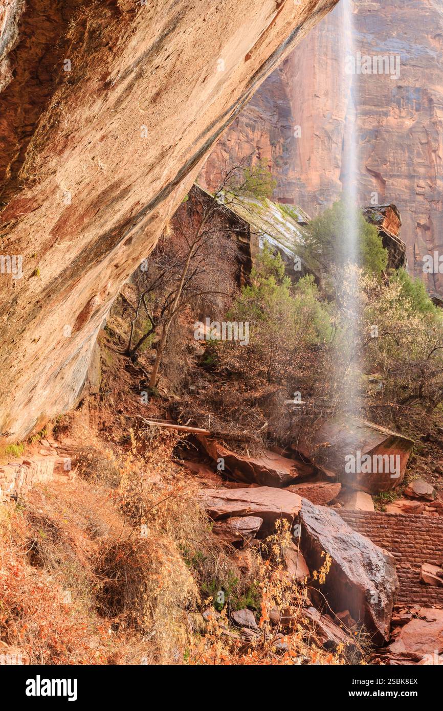 Waterfall is seen in the distance behind a rock wall. The waterfall is ...