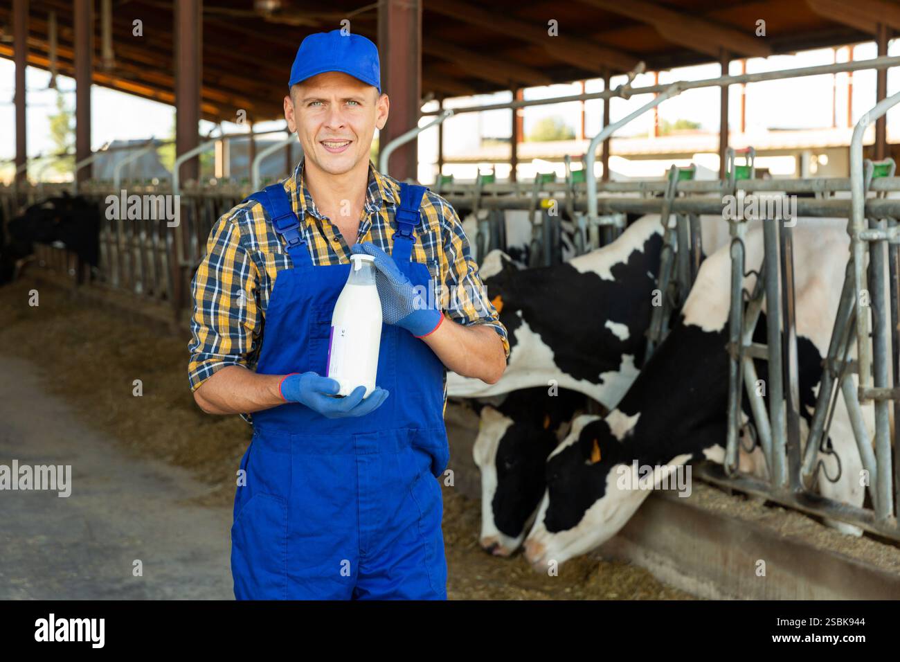 Portrait of dairy farm worker with bottle of milk in his hands against ...