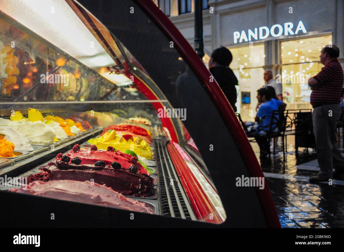 Gelato display in vibrant street, colorful flavors behind glass counter ...