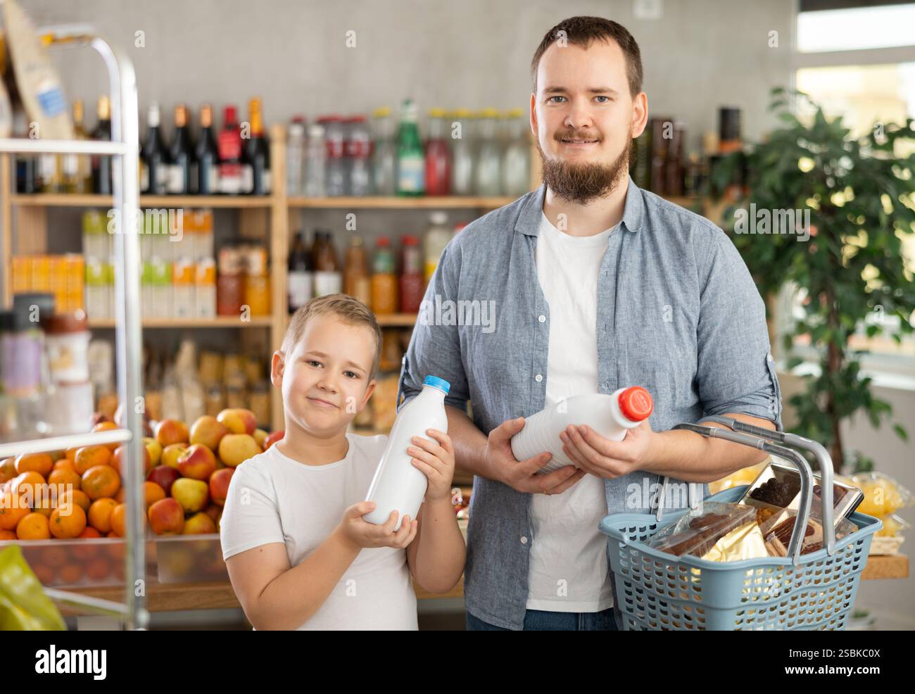 Man with son hold packages bottles and choose consider milk in store ...