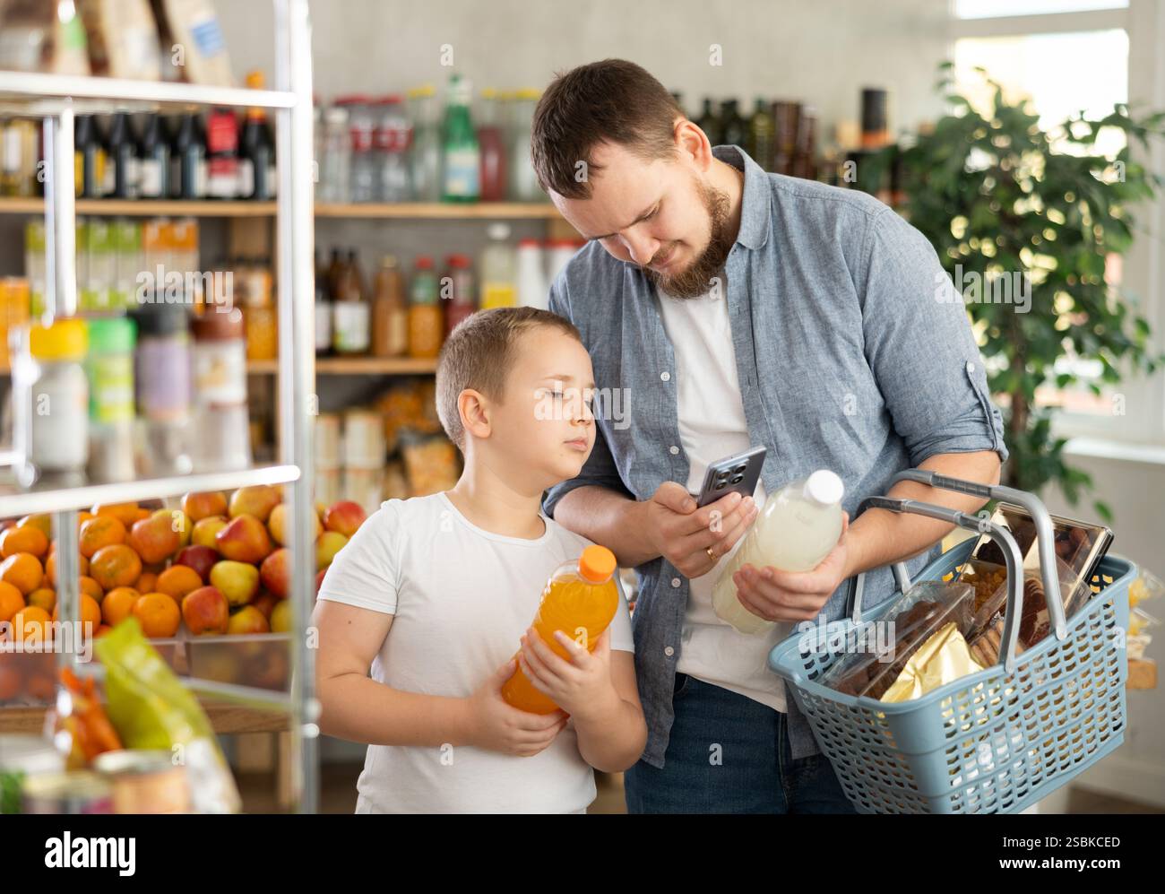 Man with preteen son scanning barcode on drink bottles in grocery store ...