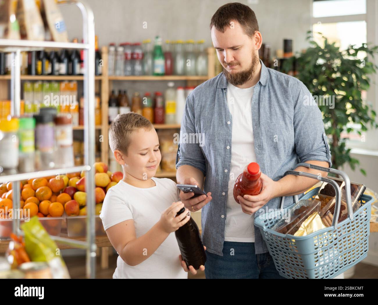 European man with son customer at shop scans QR code on juice bottle ...