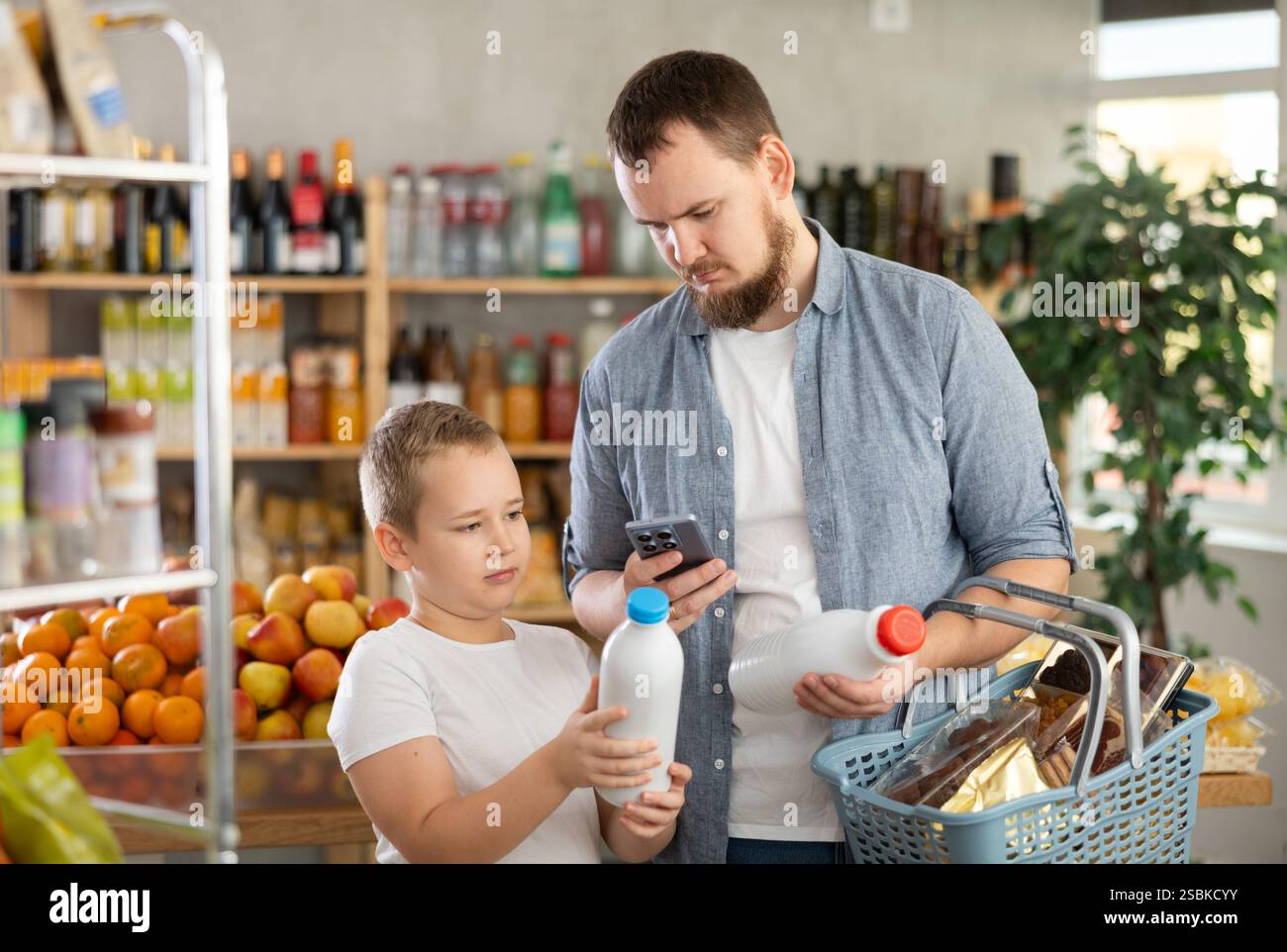 European man with son customer at shop scans QR code on milk bottle ...