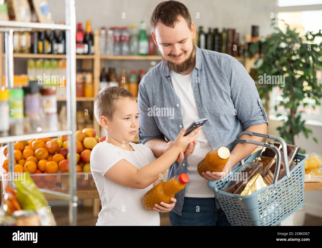 European man with son customer at shop scans QR code on juice bottle ...