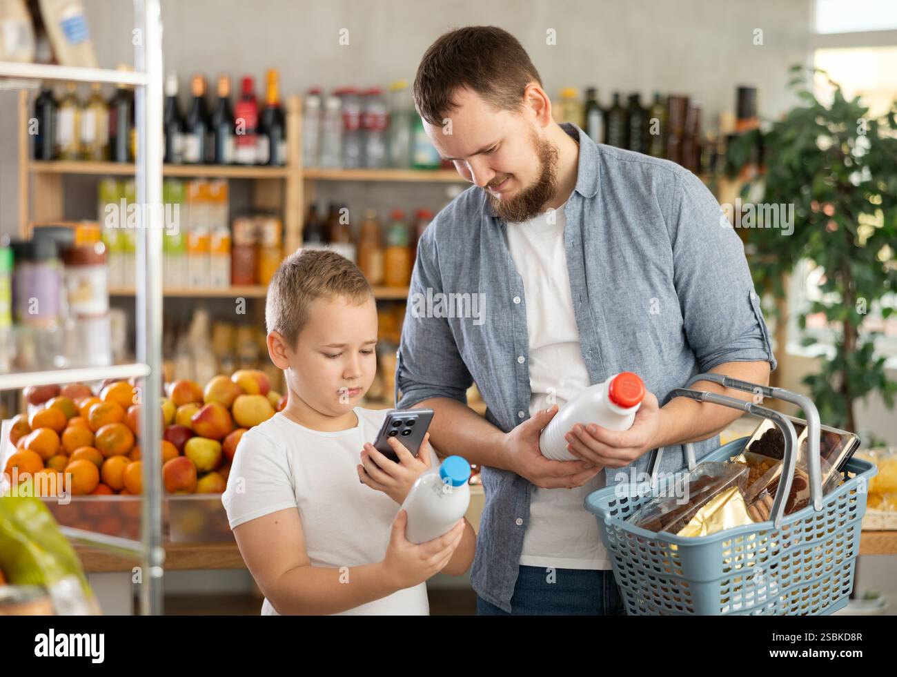 European man with son customer at shop scans QR code on milk bottle ...