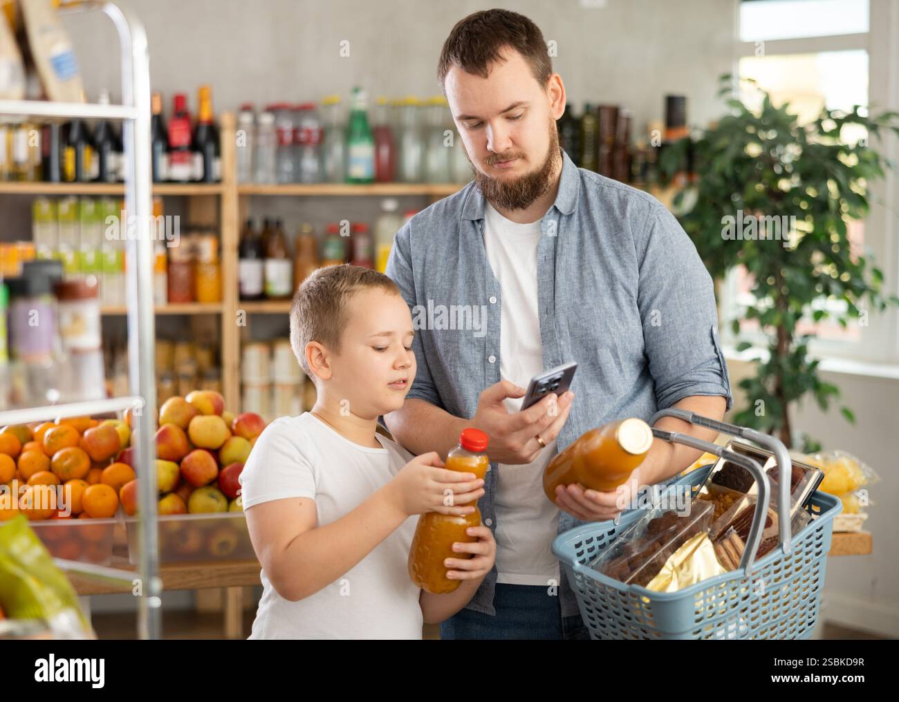 European man with son customer at shop scans QR code on juice bottle ...