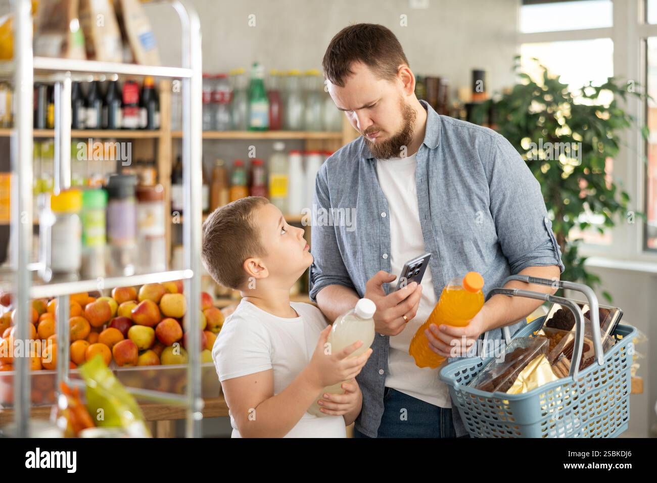 European man with son customer at shop scans QR code on drink bottle ...