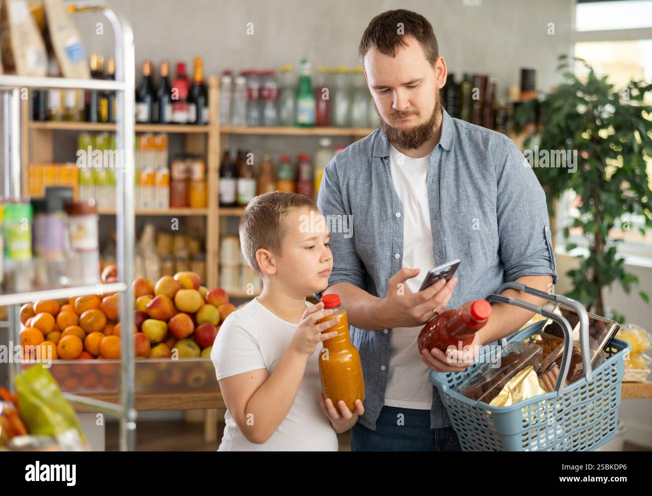 Man with preteen son scanning barcode on juice bottle with phone in ...