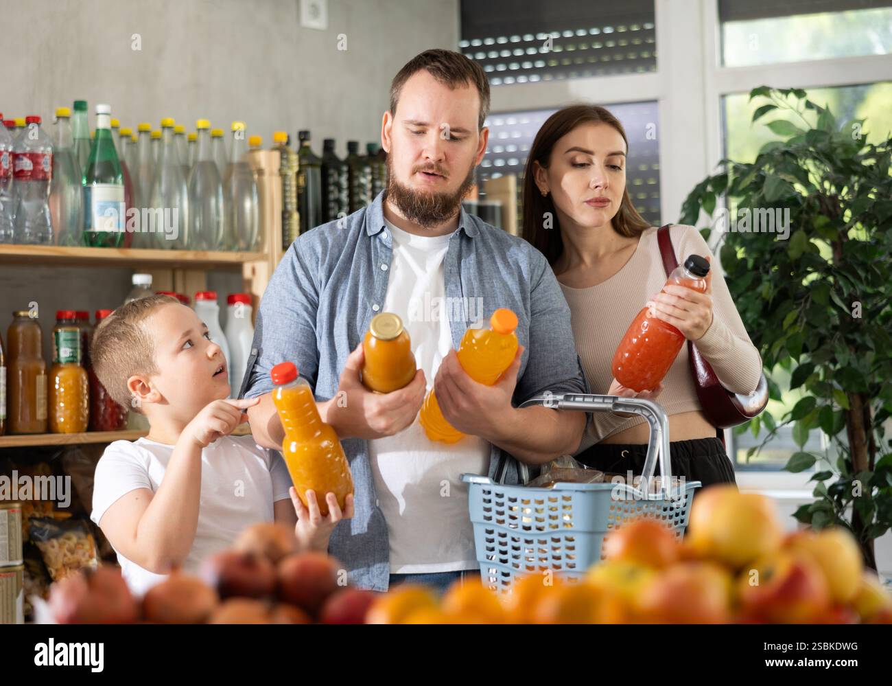 Friendly family of three choosing fruit juices in grocery store Stock ...