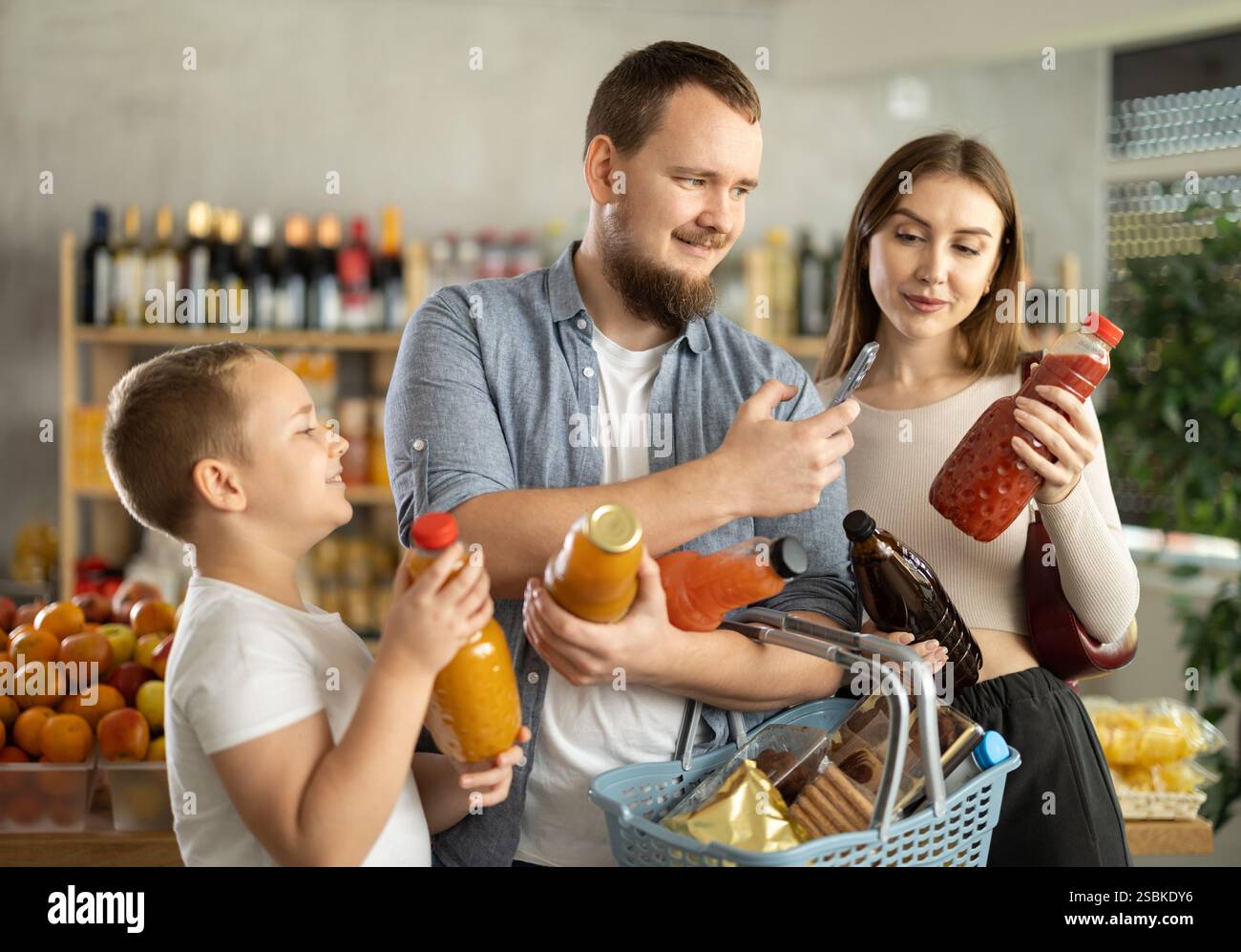Family scanning barcodes on juice bottles while shopping in supermarket ...
