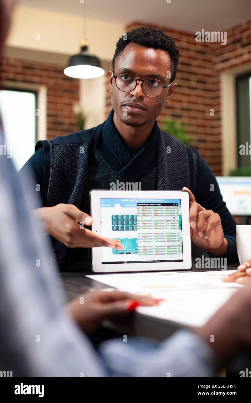 African american man holding tablet and presenting business market ...