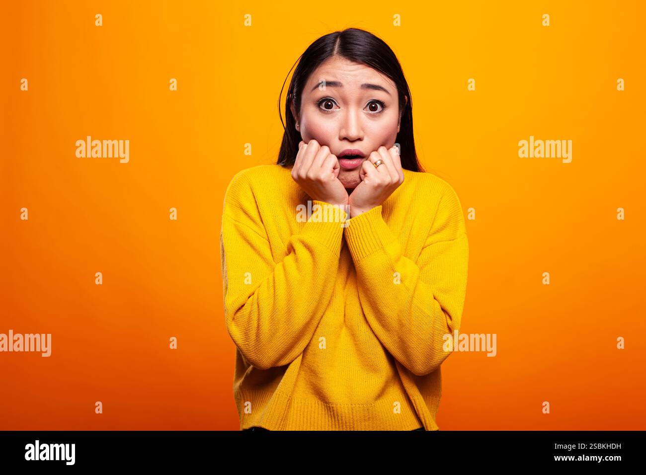 Terrified woman with her hands on face, looks at camera, expressing ...