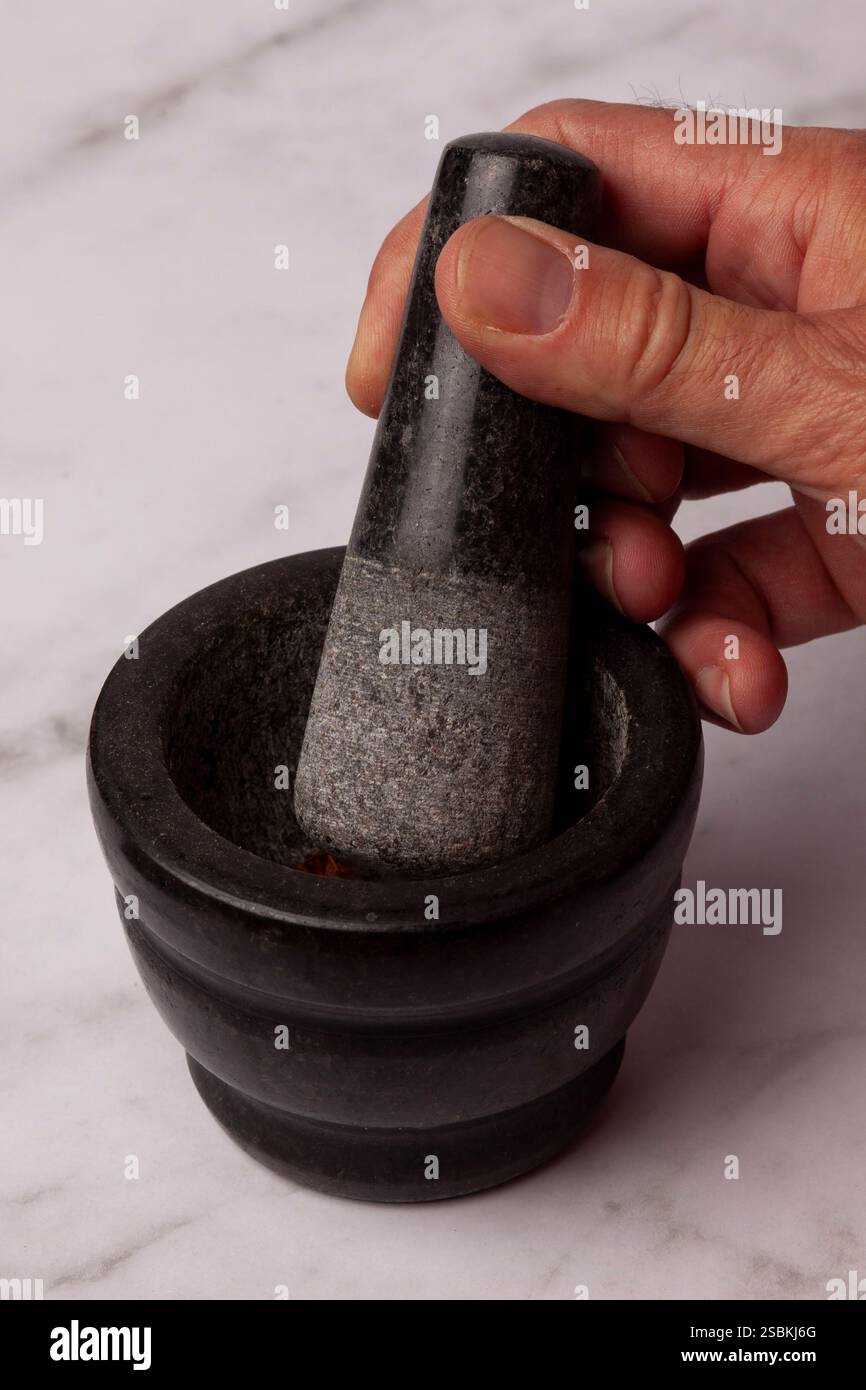Hand using a pestle and mortar Stock Photo - Alamy