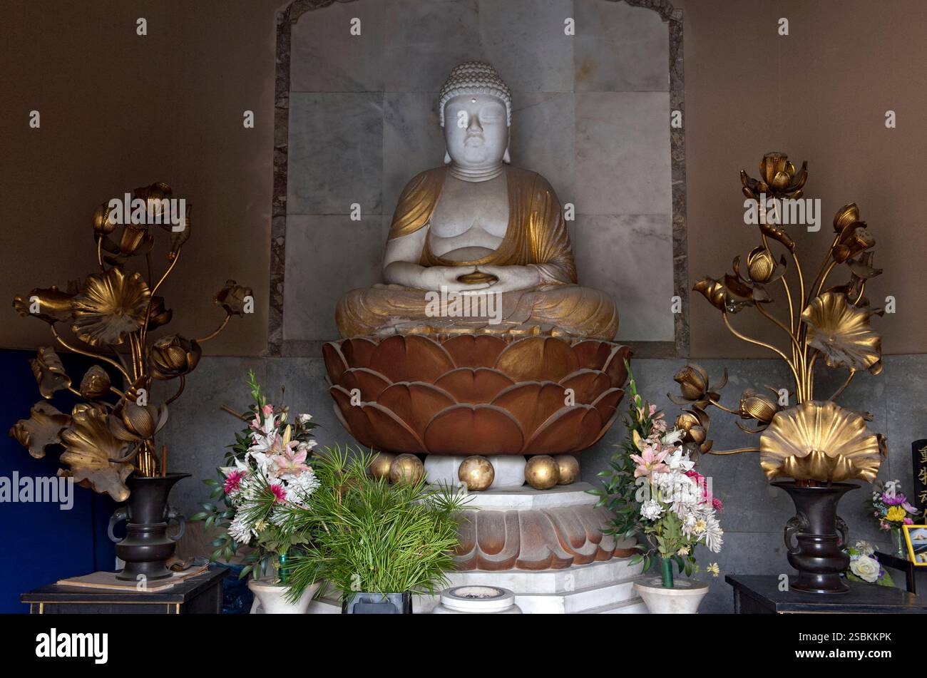 A Buddha statue sitting on a lotus flower on an altar at Ryozen Kannon ...