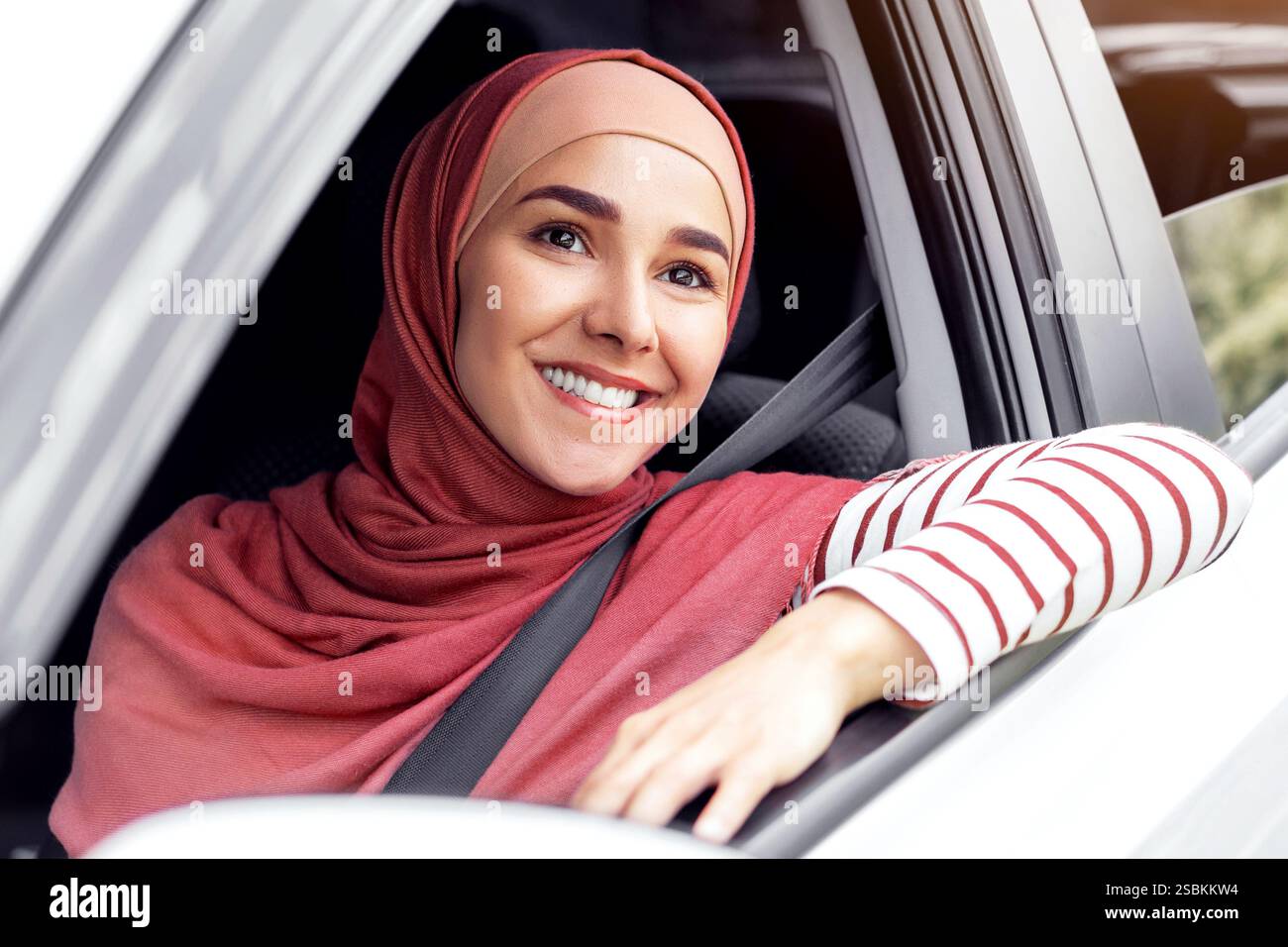 Cheerful pretty millennial middle eastern female in hijab ride in car ...