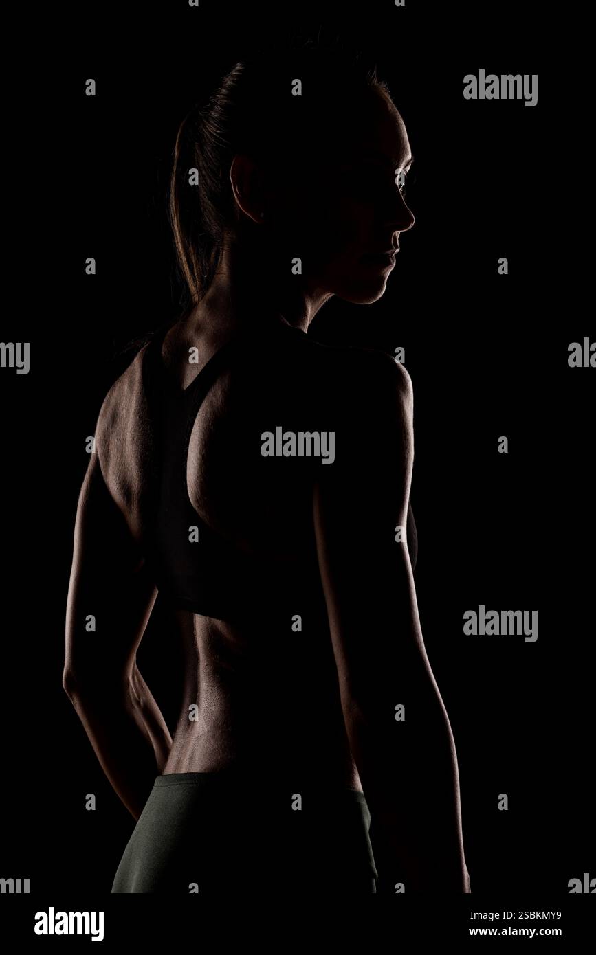 A low-light profile highlighting the muscular back and toned physique ...