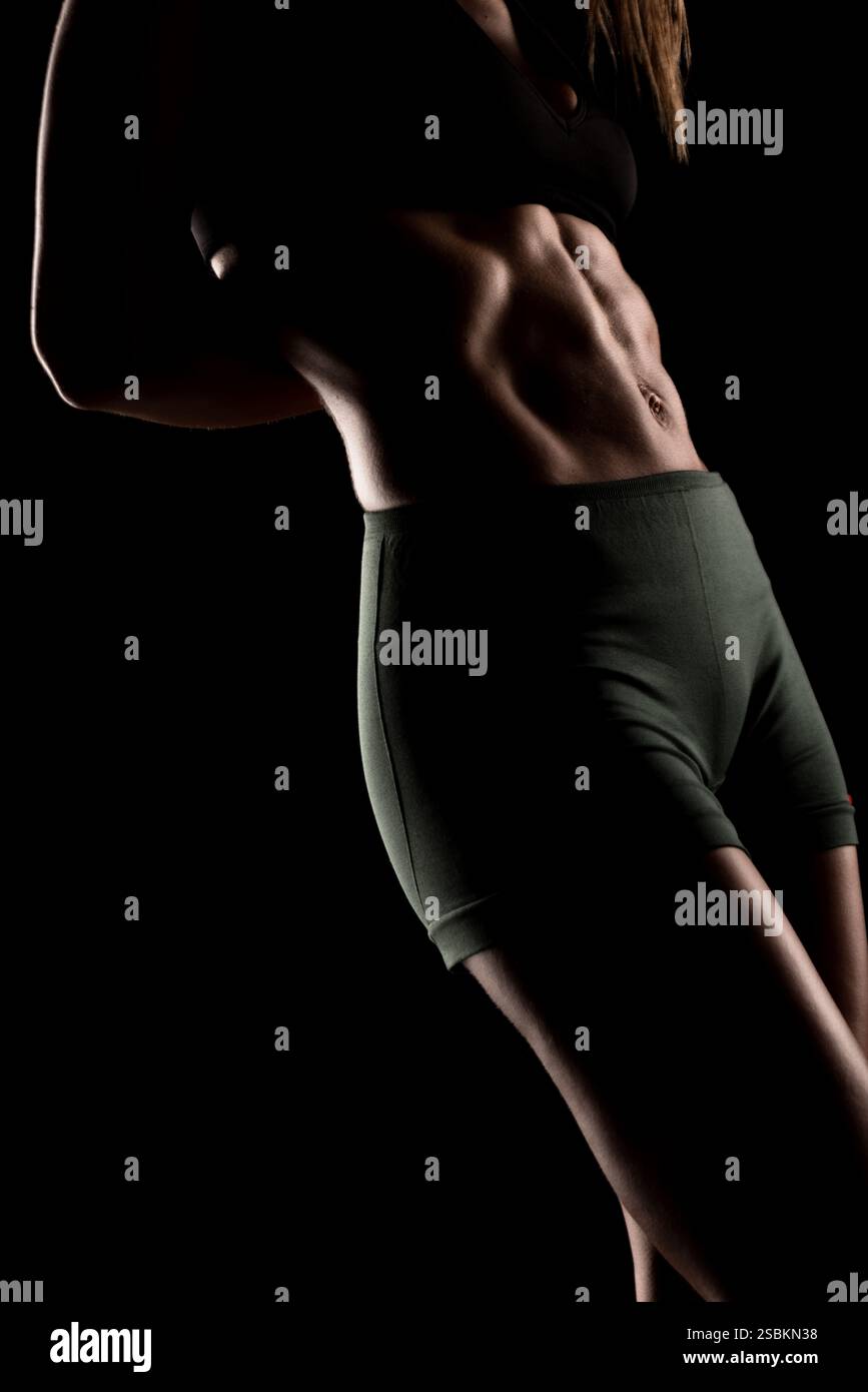 A fit woman with a toned body highlights her strong core muscles ...