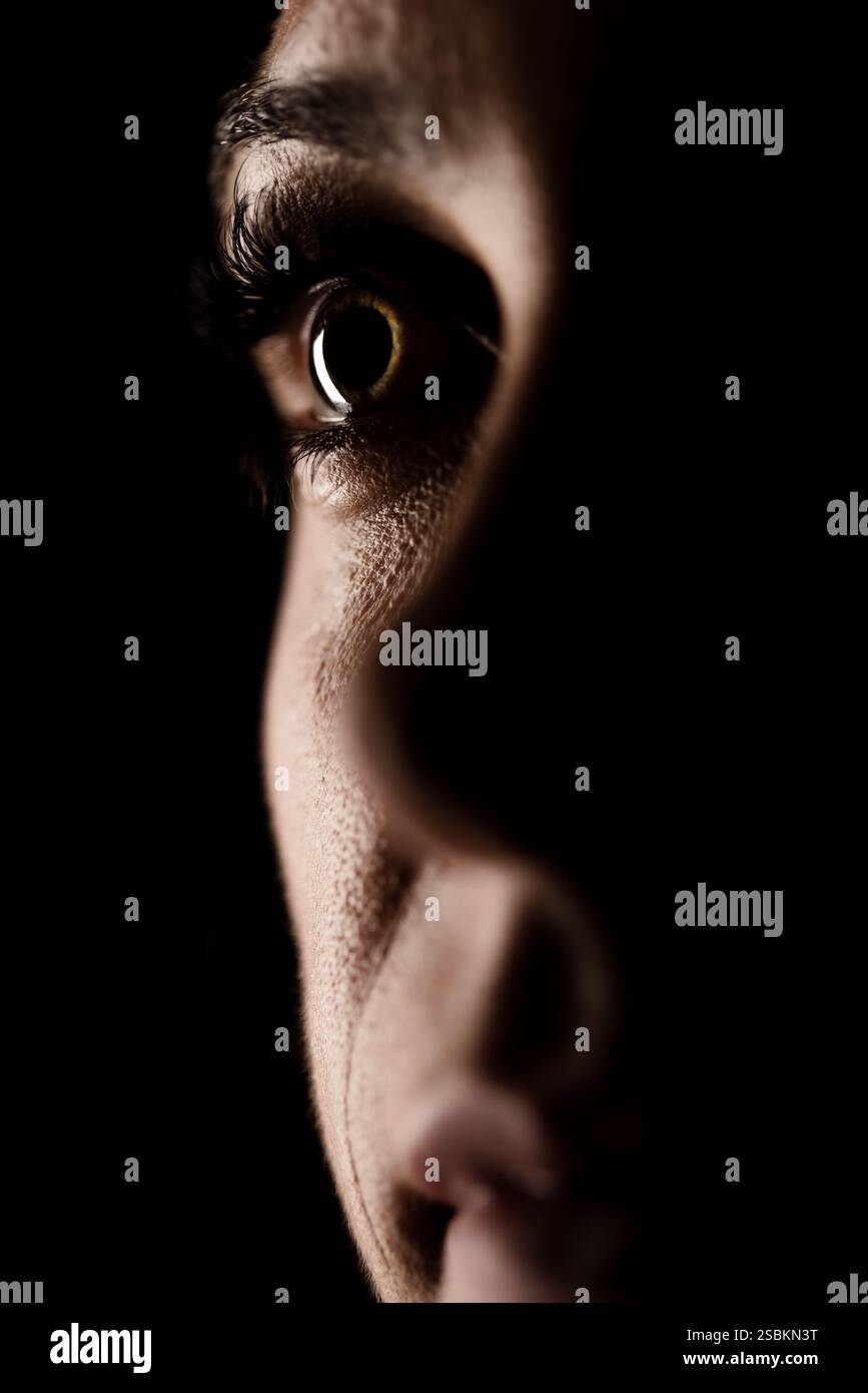 Close-up photograph of one human eye highlighted by soft, dim lighting ...