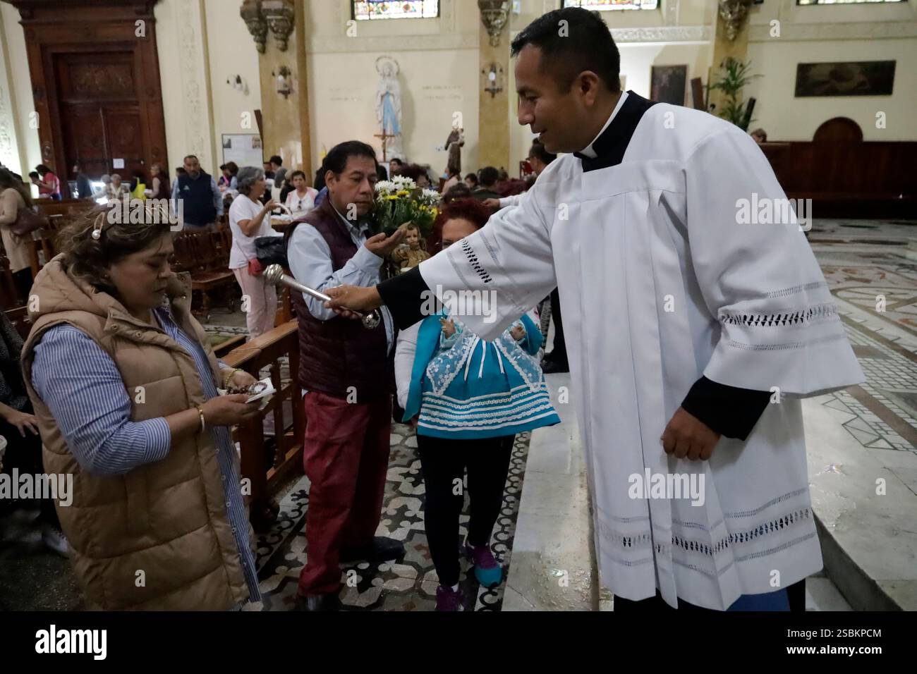 A priest blesses the figures of the baby Jesus during a mass at the Templo de Nuestra Señora de ...