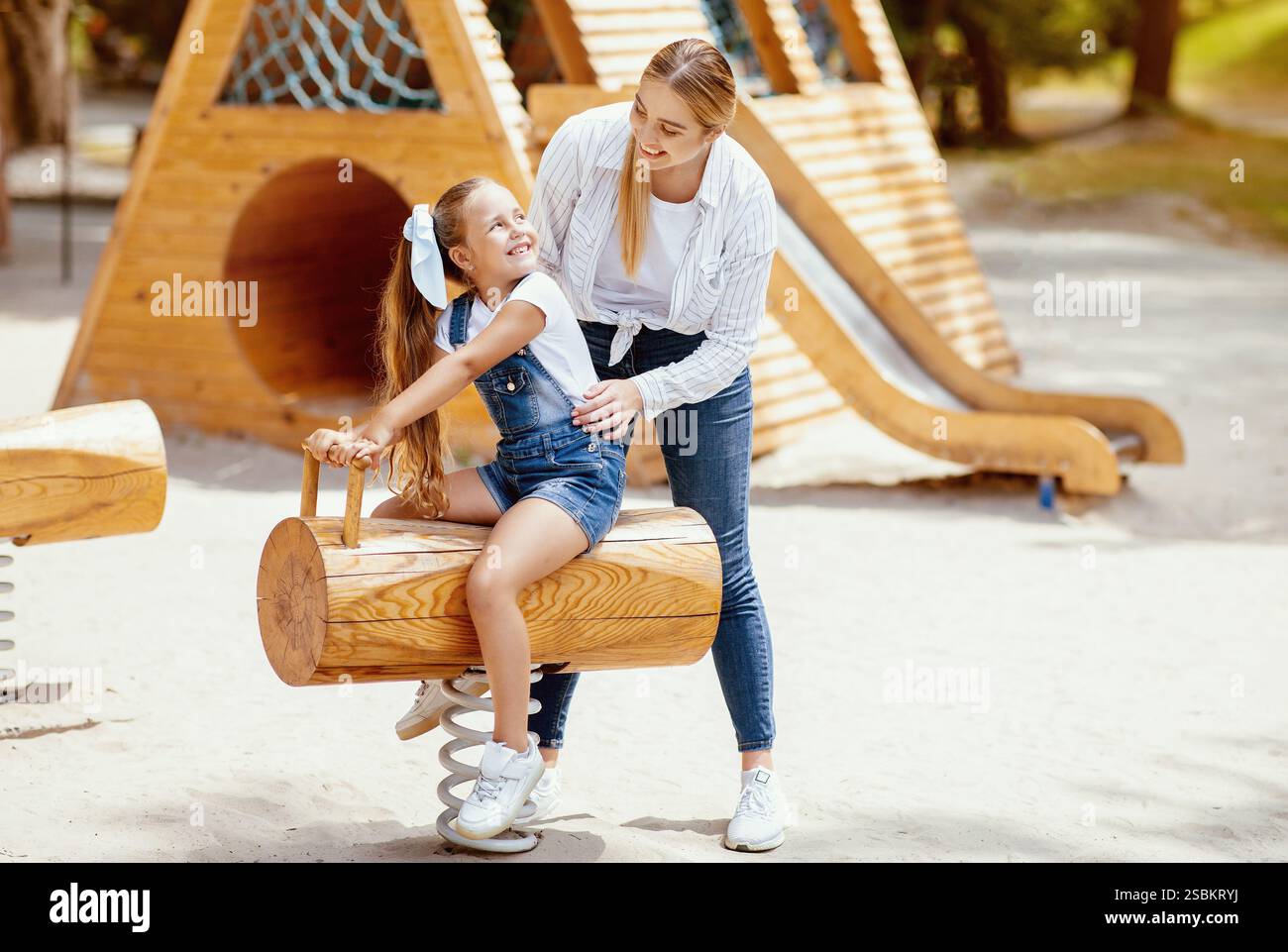 Mother Pushing Daughter On Swing Having Fun On Playground Outside Stock Photo - Alamy
