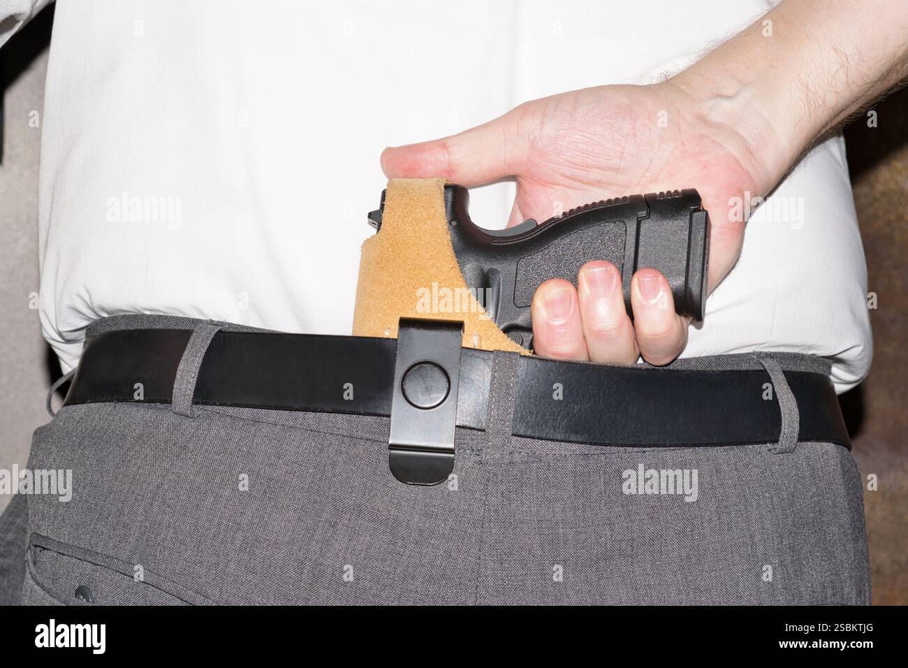 Hand reaching for gun behind the back holster draw concealed carry self ...