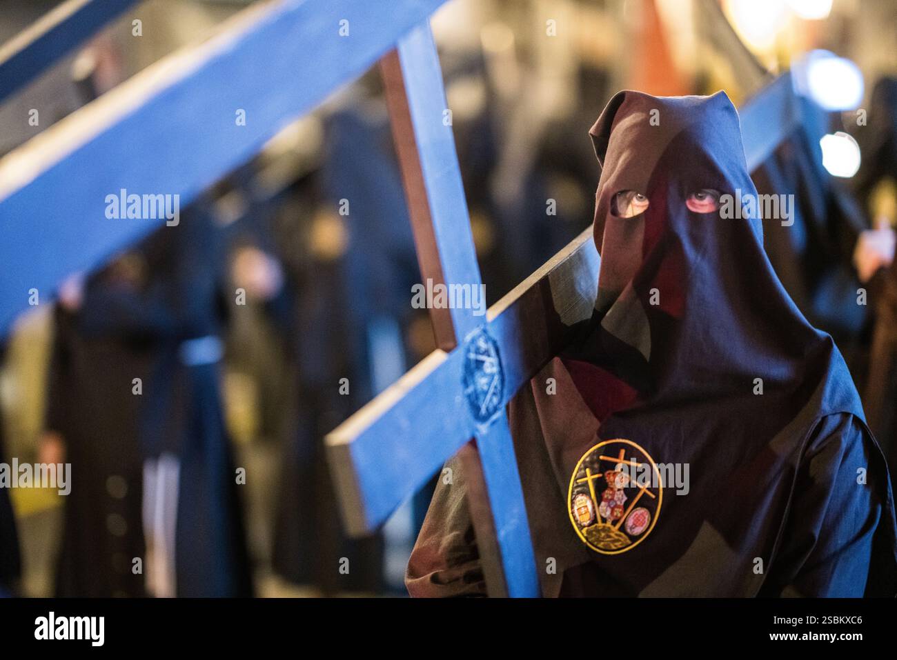 Penitent carrying cross during Semana Santa procession in Seville ...