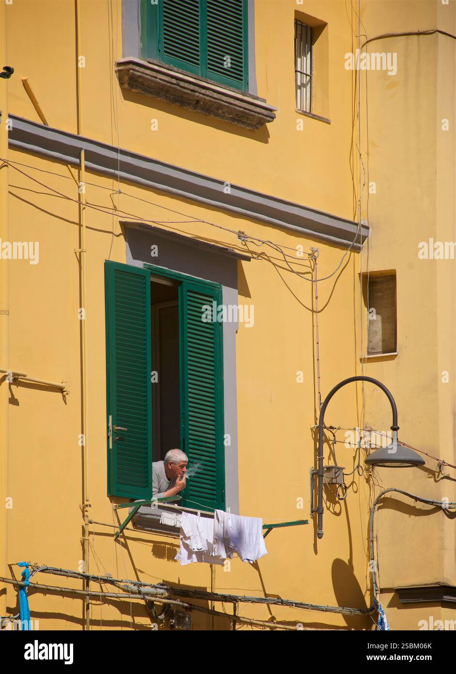 A typical Neapolitan street scene... Man smoking window in central ...