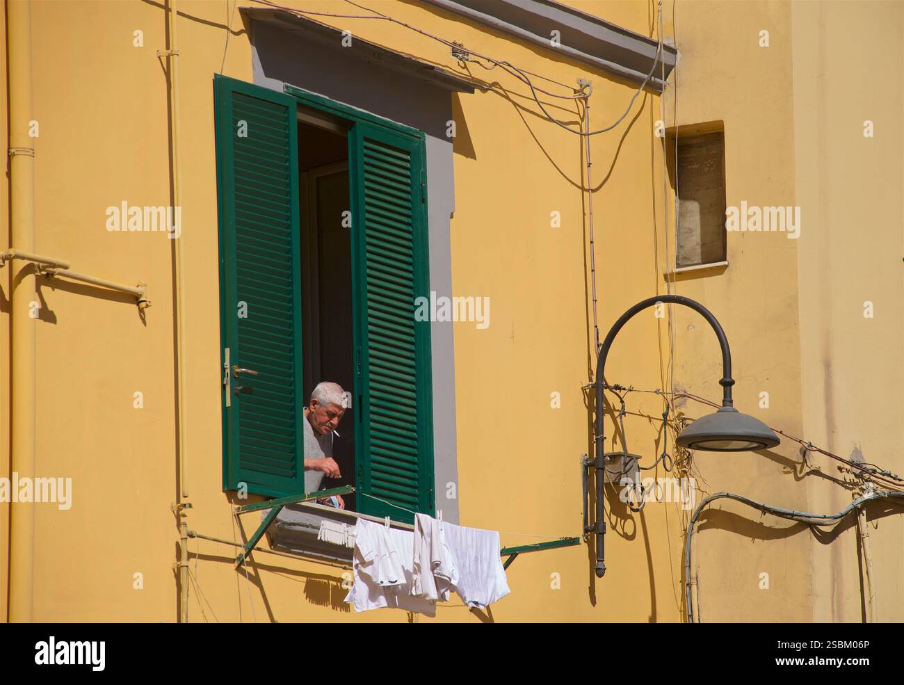 A typical Neapolitan street scene... Man smoking window in central ...