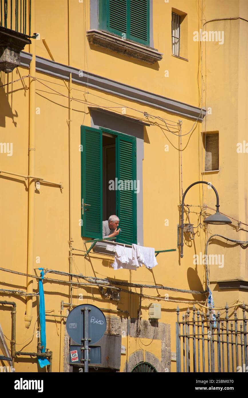 A typical Neapolitan street scene... Man smoking window in central ...