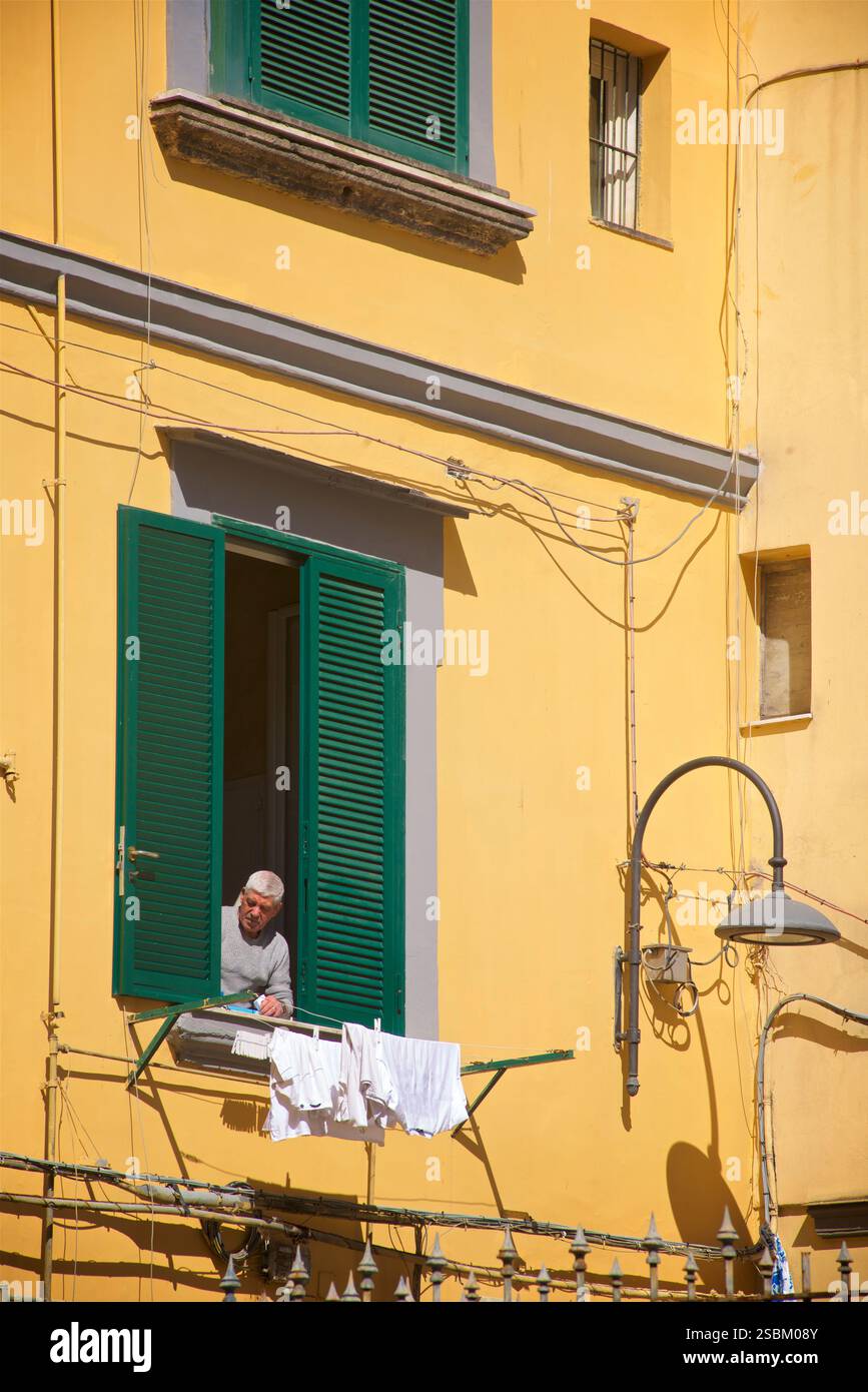 A typical Neapolitan street scene... Man looking our from a window in ...