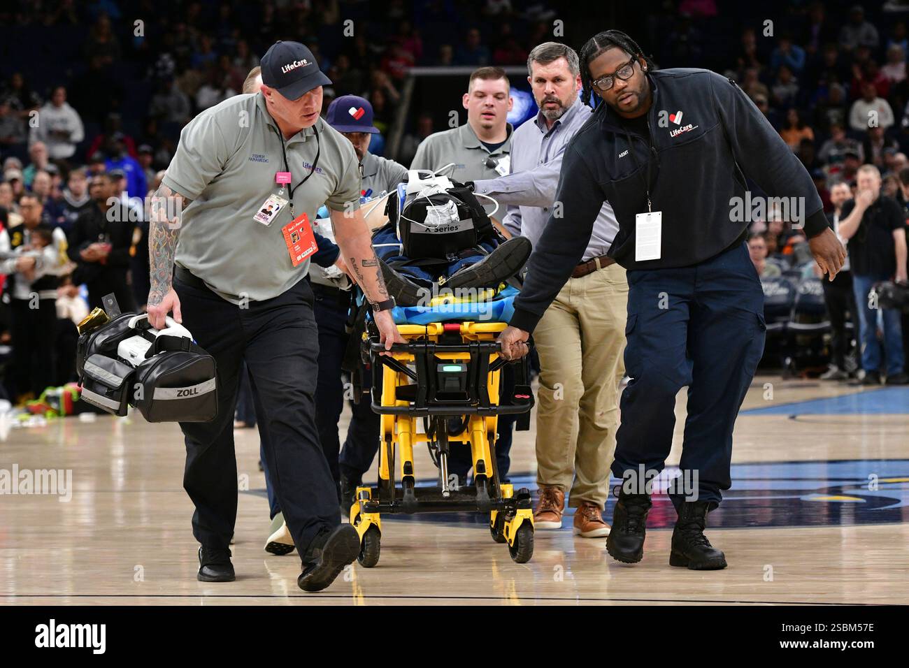 Medical personnel wheel a man off of the court after he collapsed ...