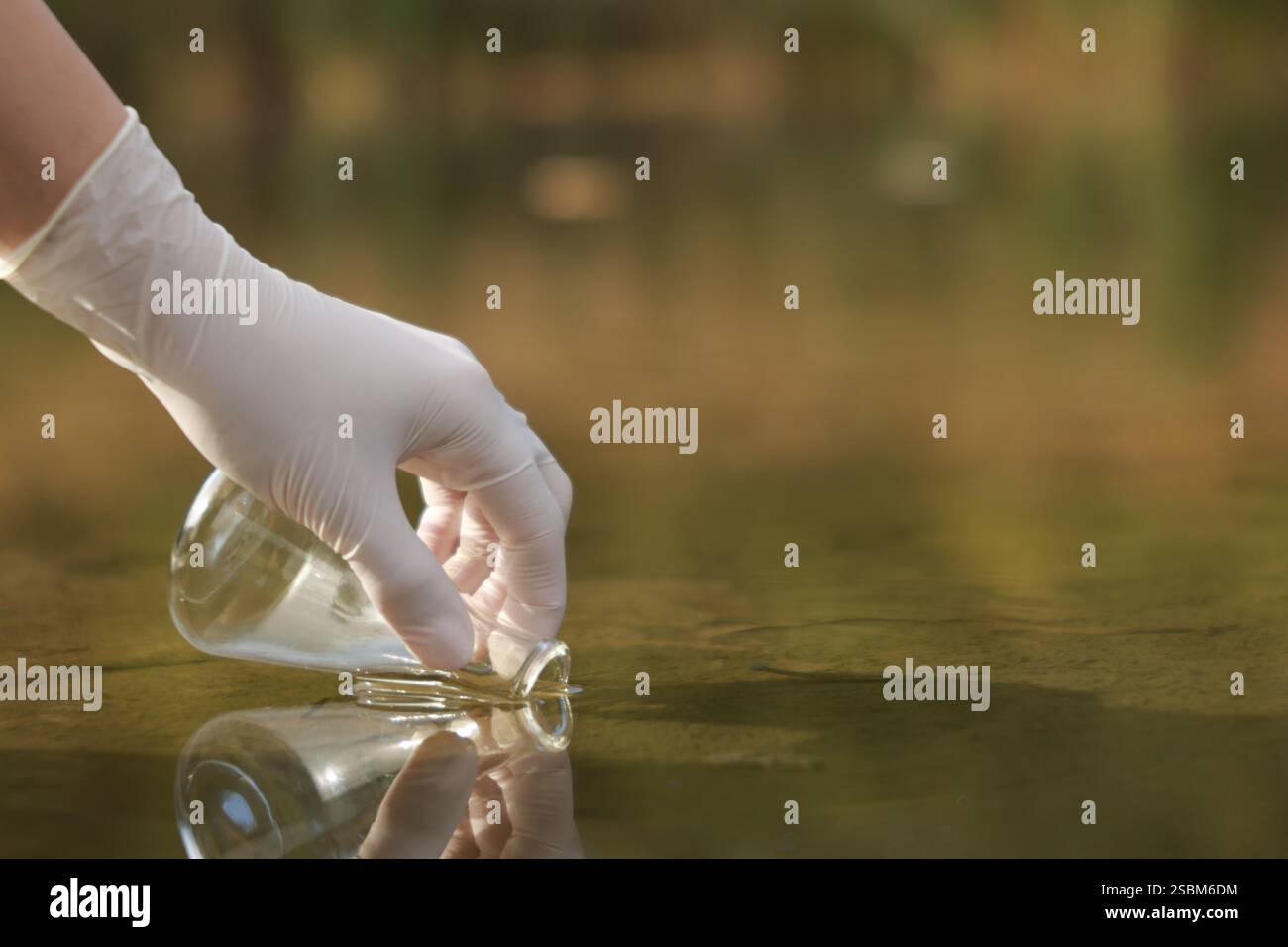 Examination of water quality. Researcher taking water sample from lake ...
