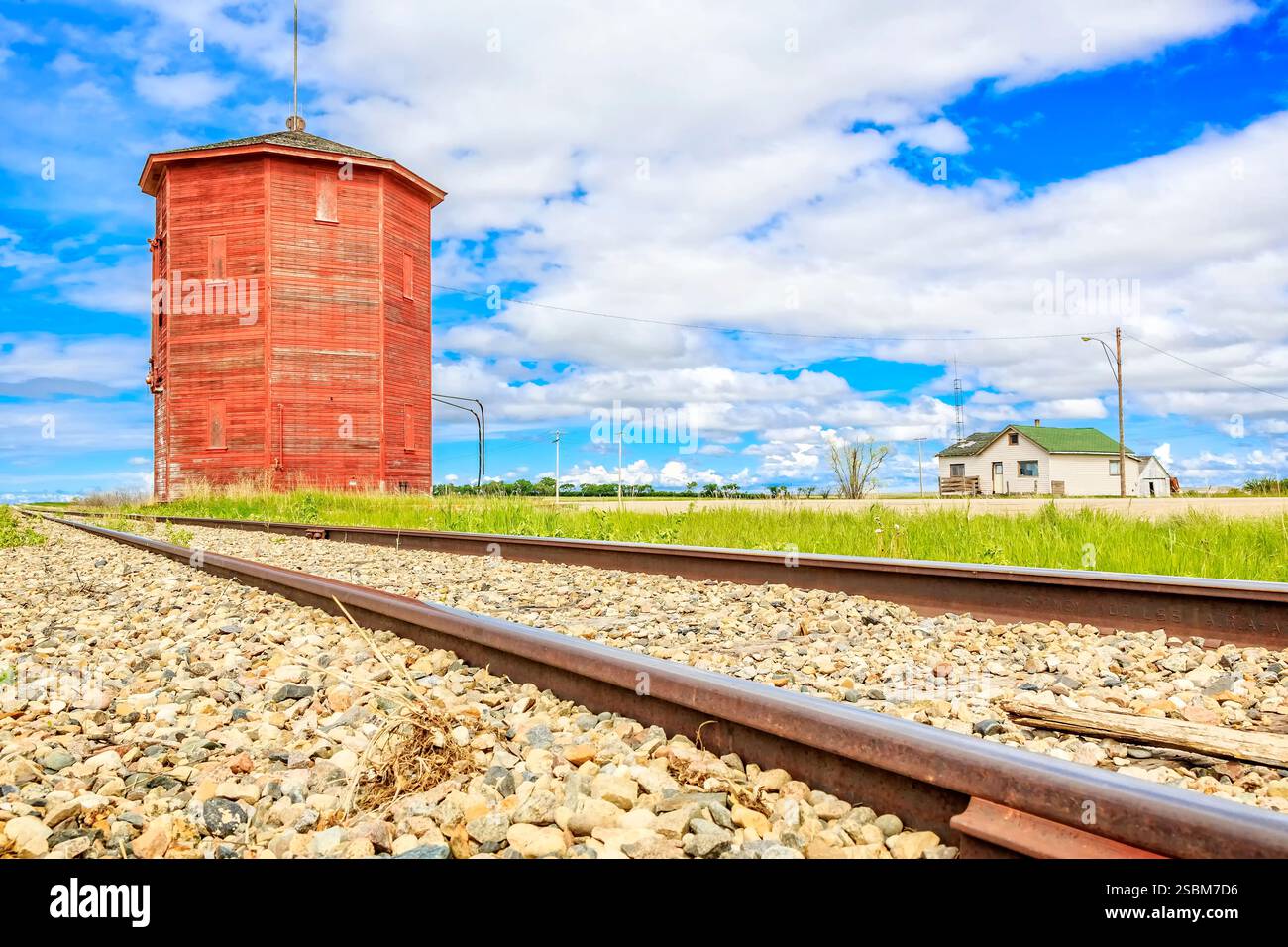Red water tower is next to a railroad track. The water tower is old and ...