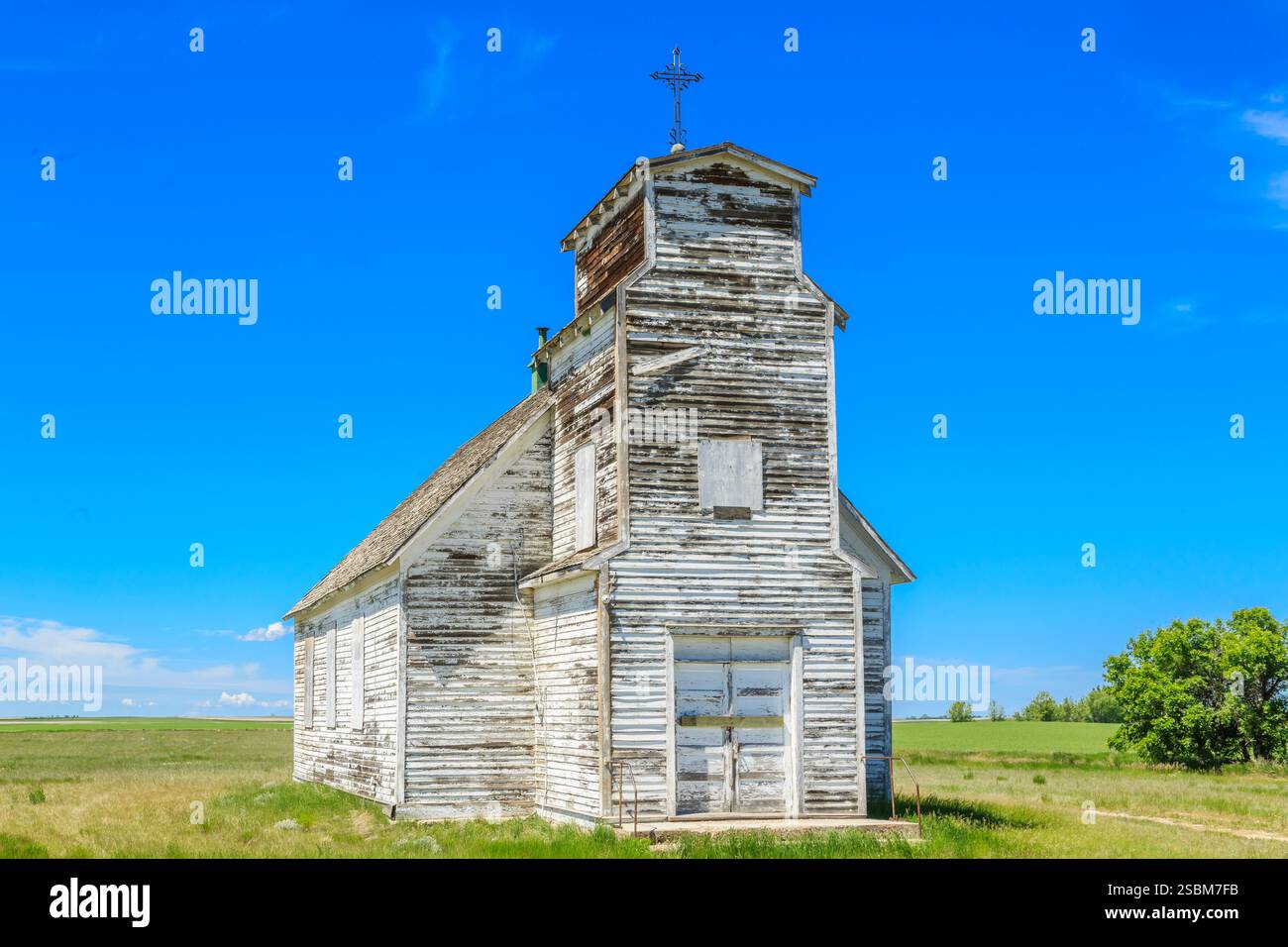 White church with a cross on top. The roof is missing shingles. The ...