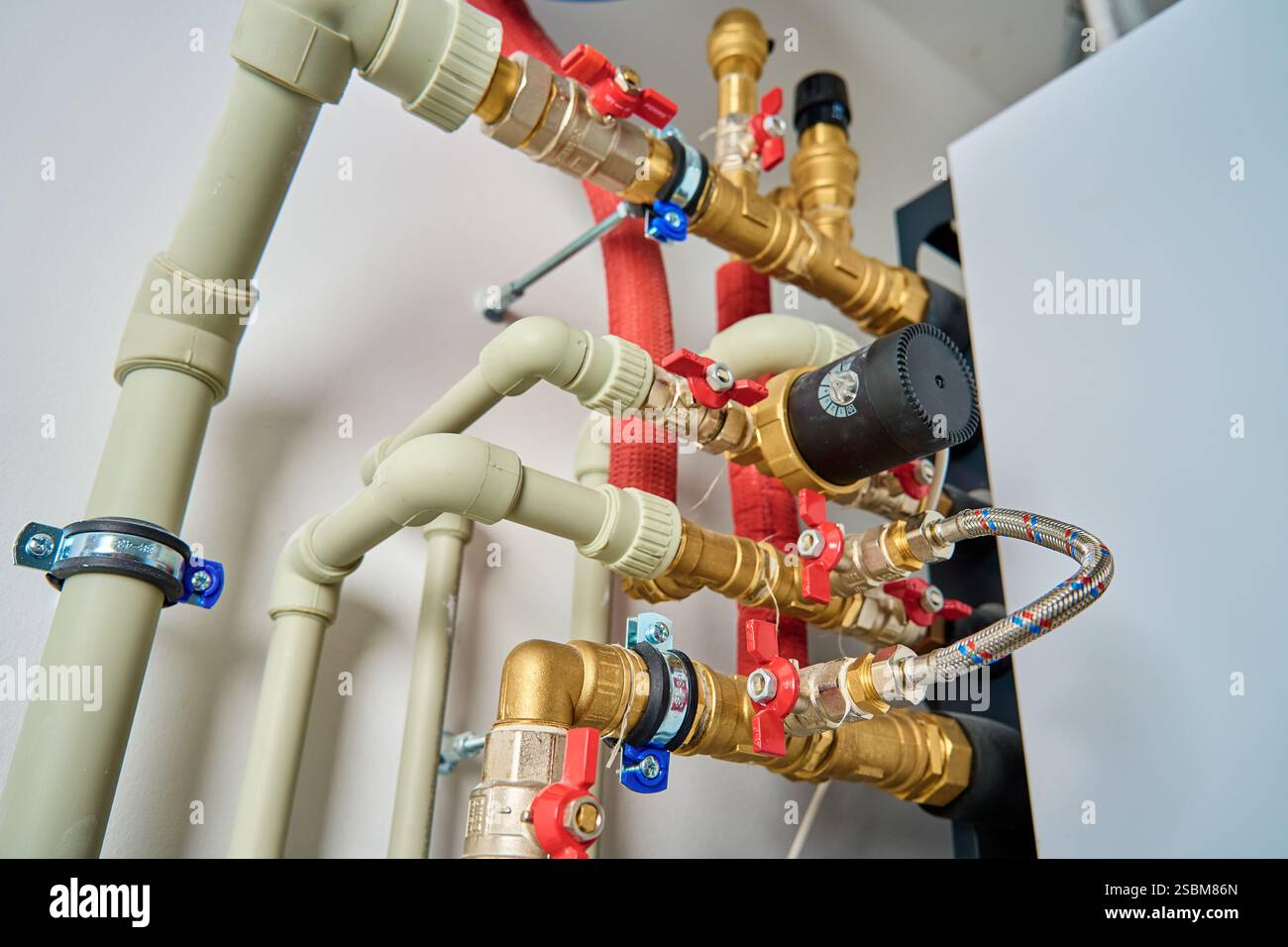 Close-up of heating system featuring plastic pipes, brass fittings, and ...