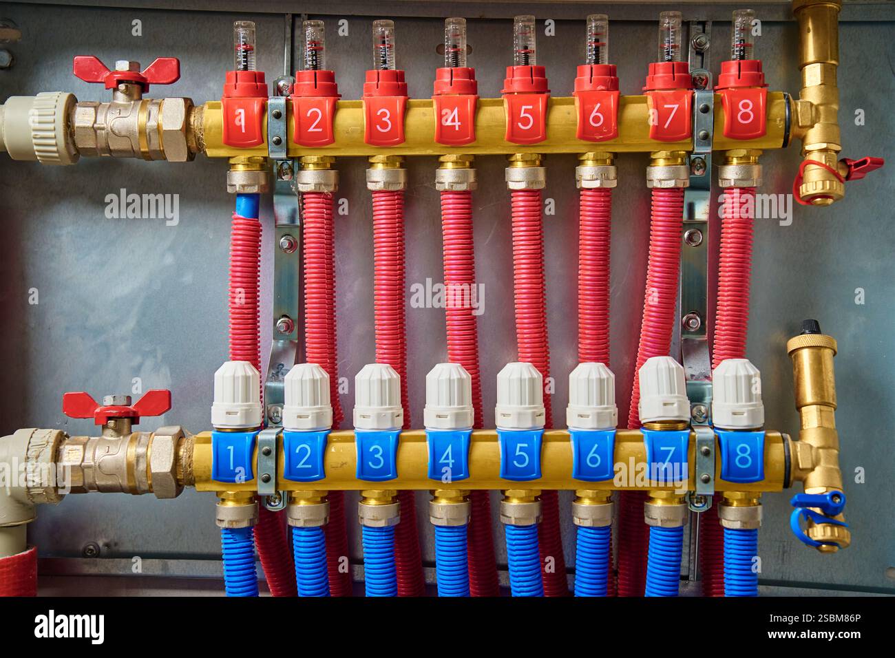 Close-up of underfloor heating manifold featuring brass pipes, control ...