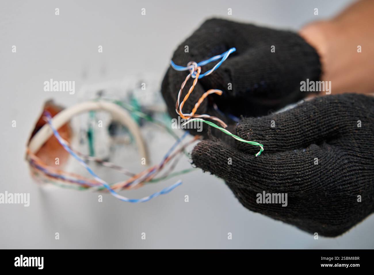 Technician wearing black gloves repairing network cables in wall socket ...