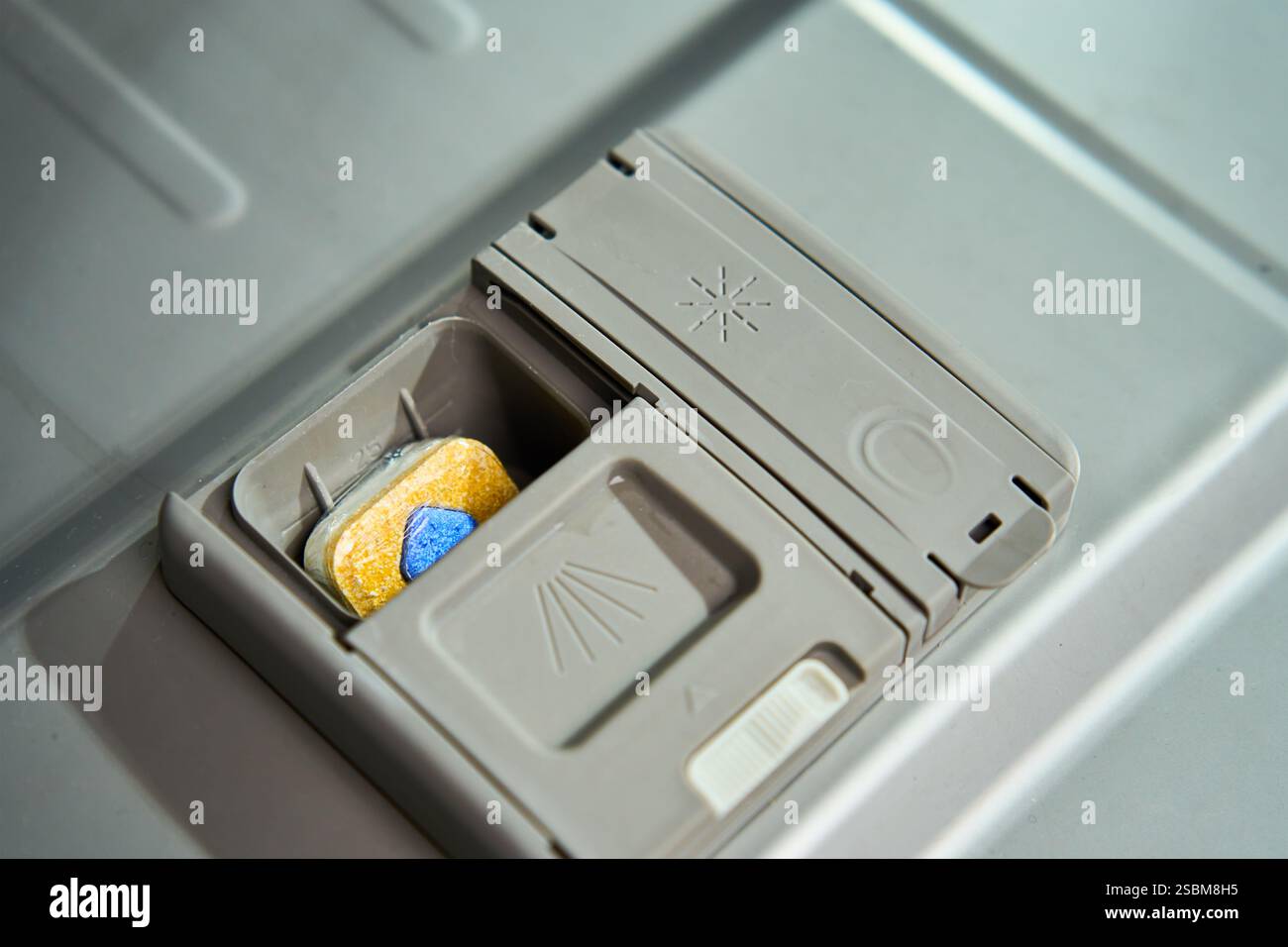 Close-up of dishwasher detergent tablet placed inside dispenser ...