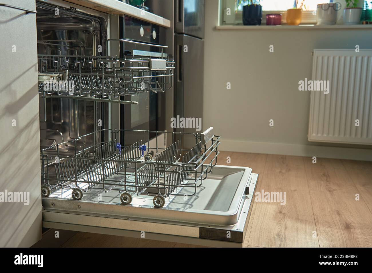 Open empty dishwasher with empty racks and extended basket in modern ...