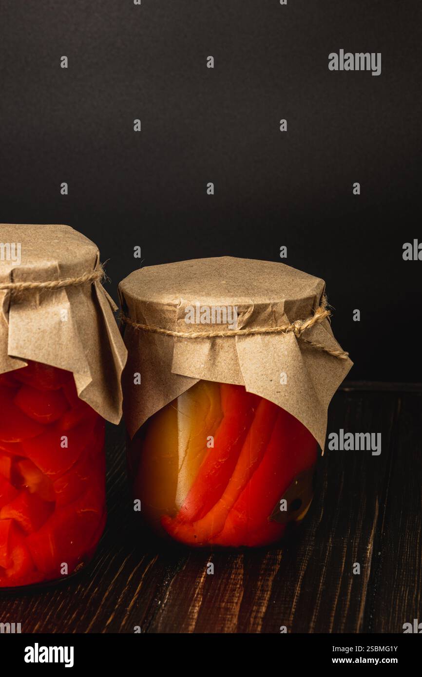 Glass jars filled with vibrant pickled peppers and salted lard are ...