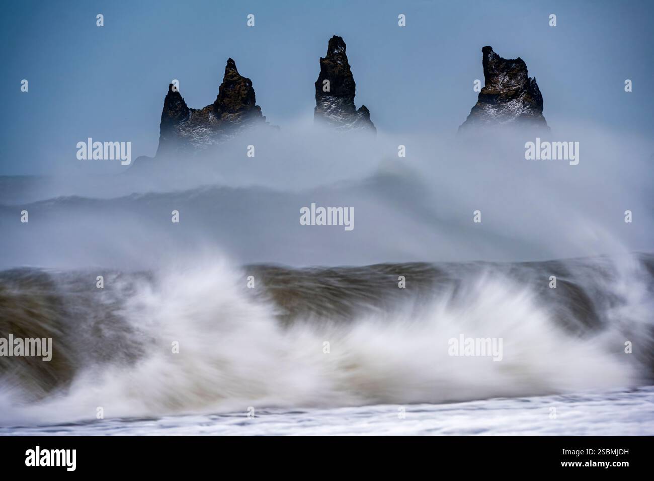 Panoramic view of ocean waves with protruding rocks from black sand ...