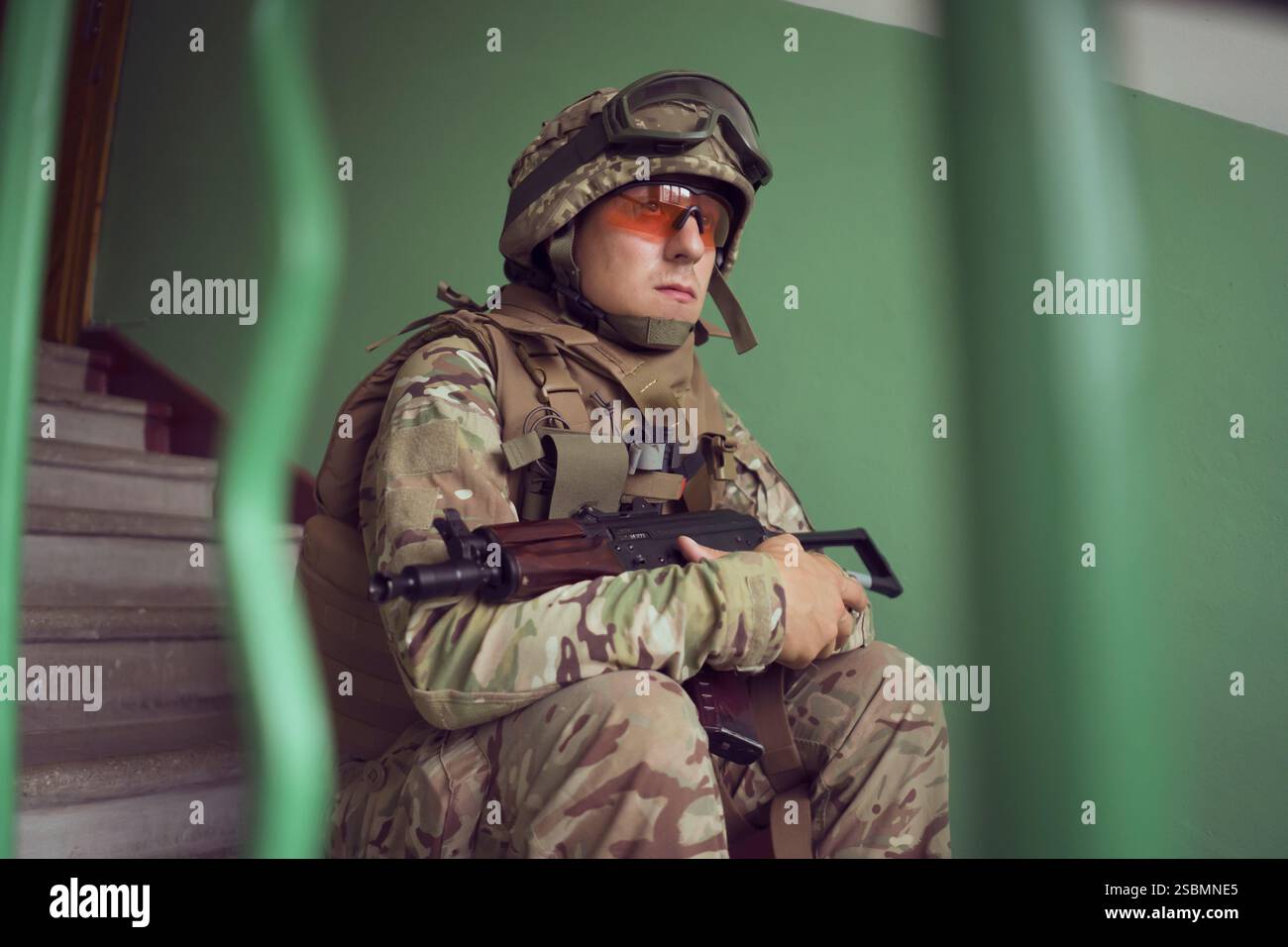 A soldier sits on the stairs with a weapon., machine gun Stock Photo ...