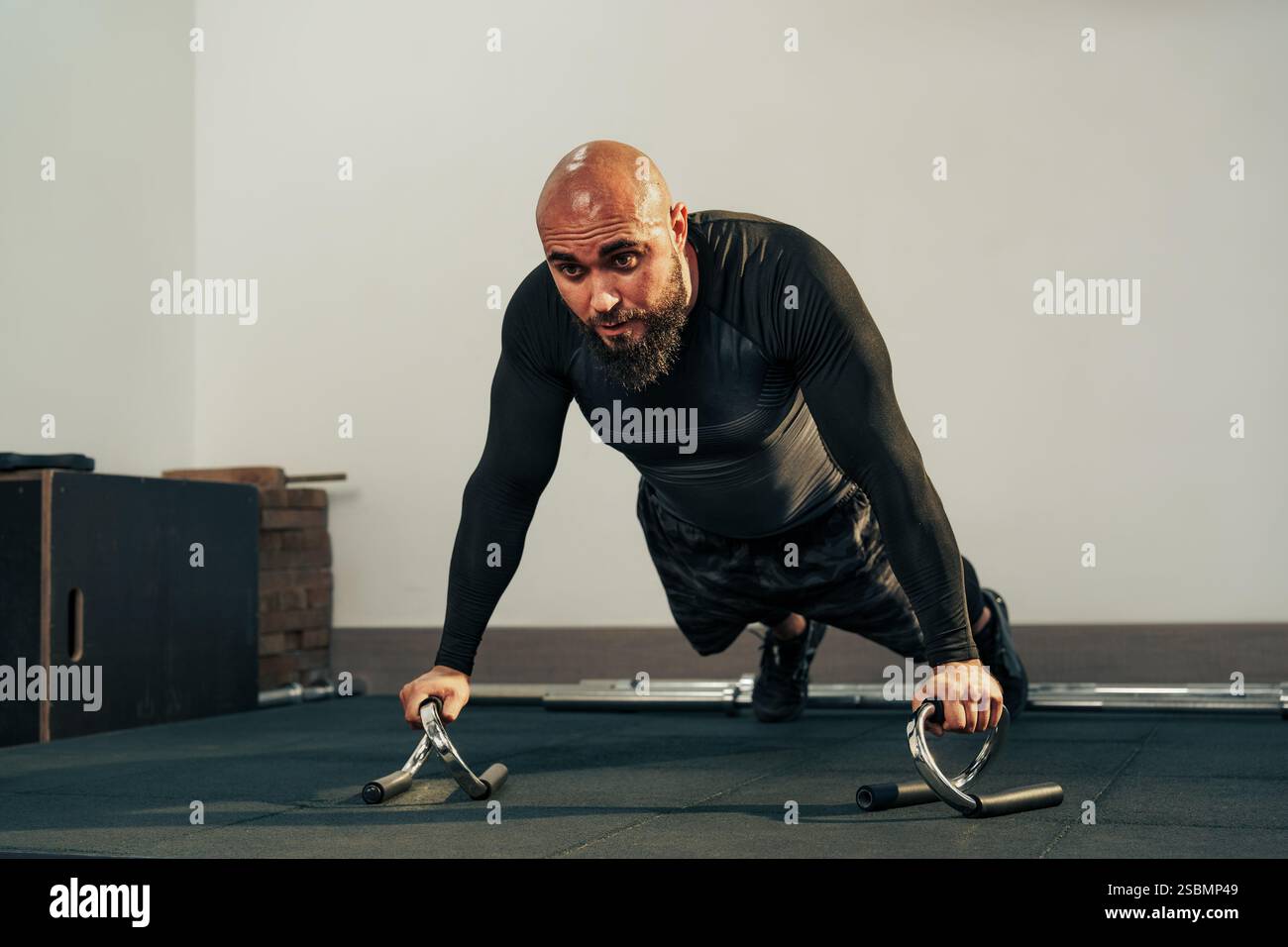 Man performing push-ups using handles in an indoor gym setting during ...